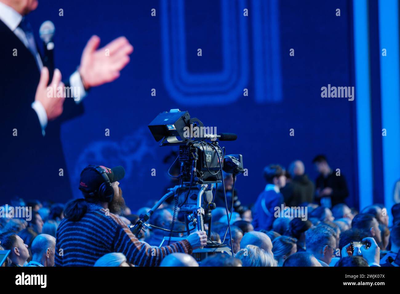 A professional cameraman films a speaker at an event, capturing the ...