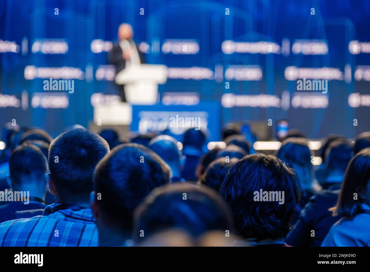 Blurred speaker presenting to an attentive audience at a professional ...