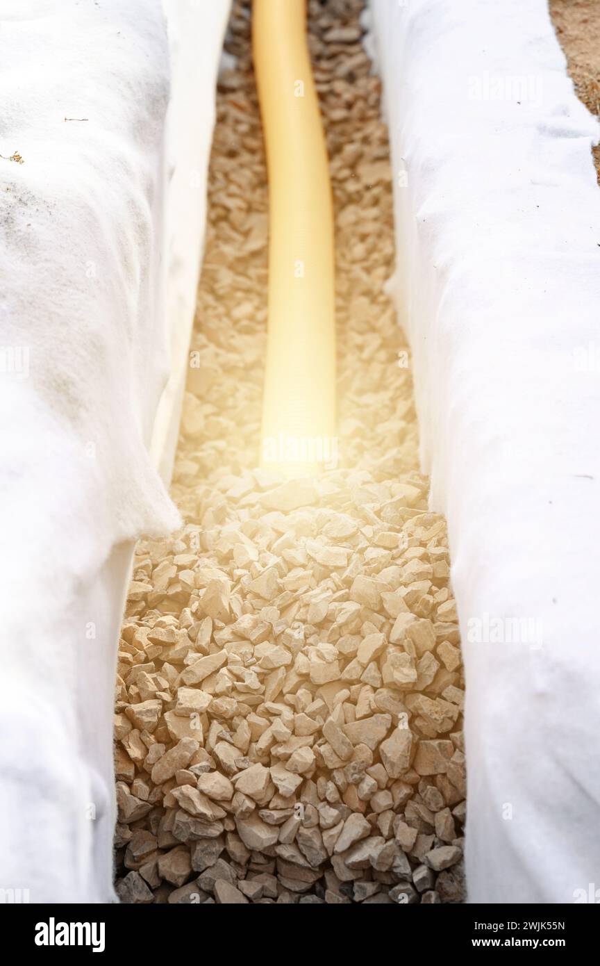 Yellow corrugated pipe with perforation in a trench with crushed stone ...