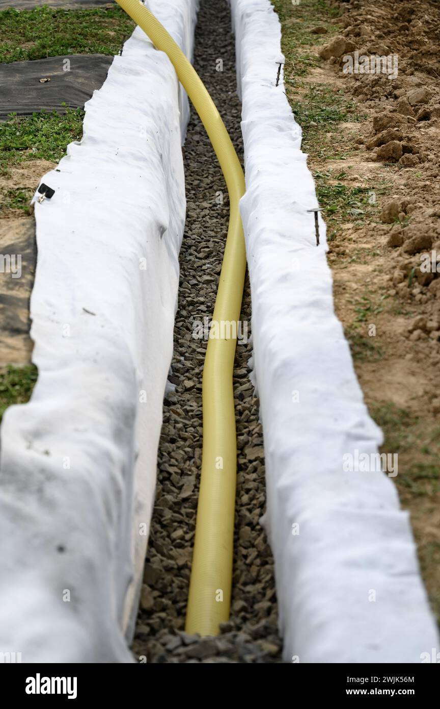 Yellow corrugated pipe with perforation in a trench with crushed stone ...