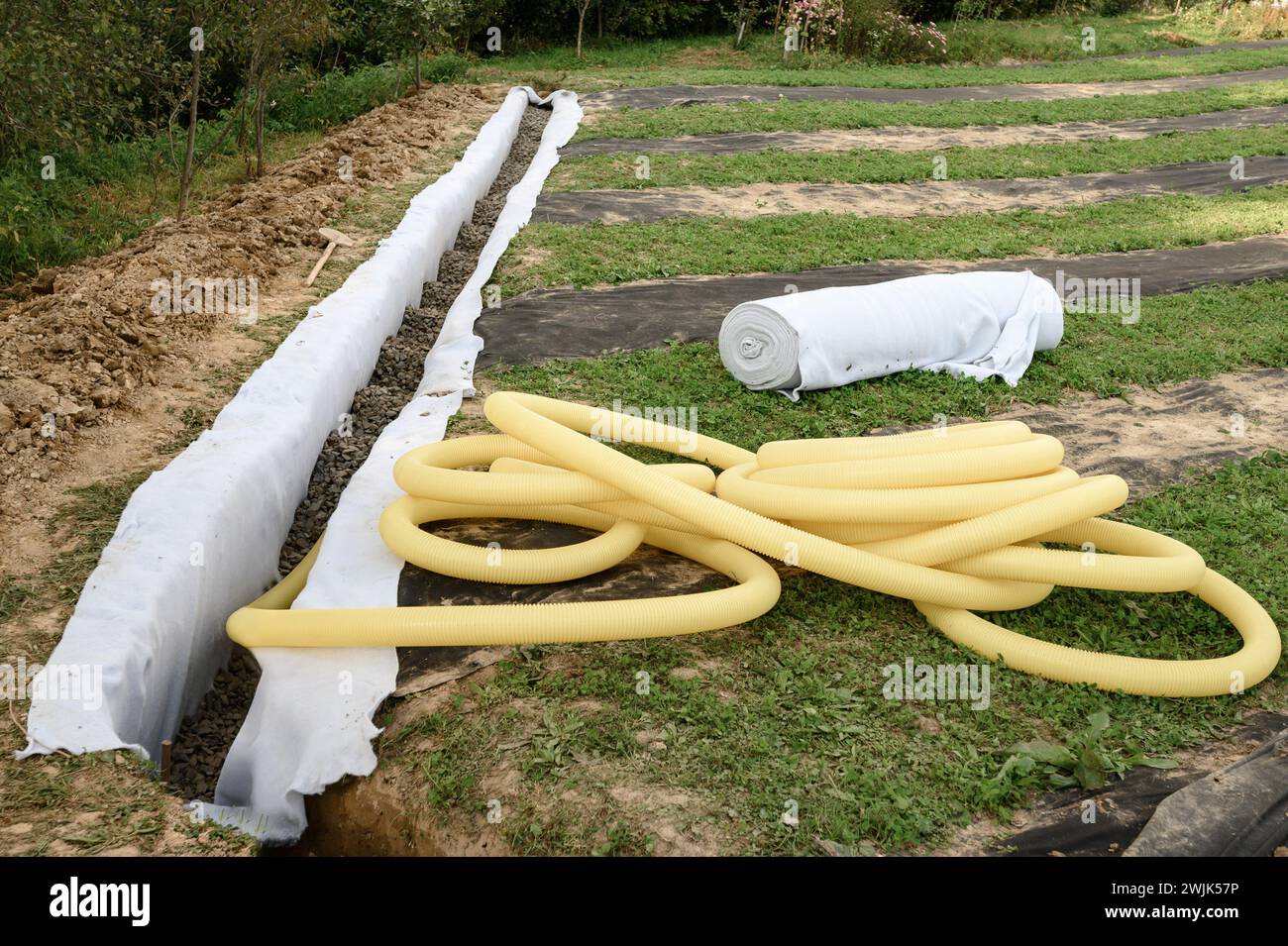 Yellow corrugated pipe with perforation in a trench with crushed stone ...