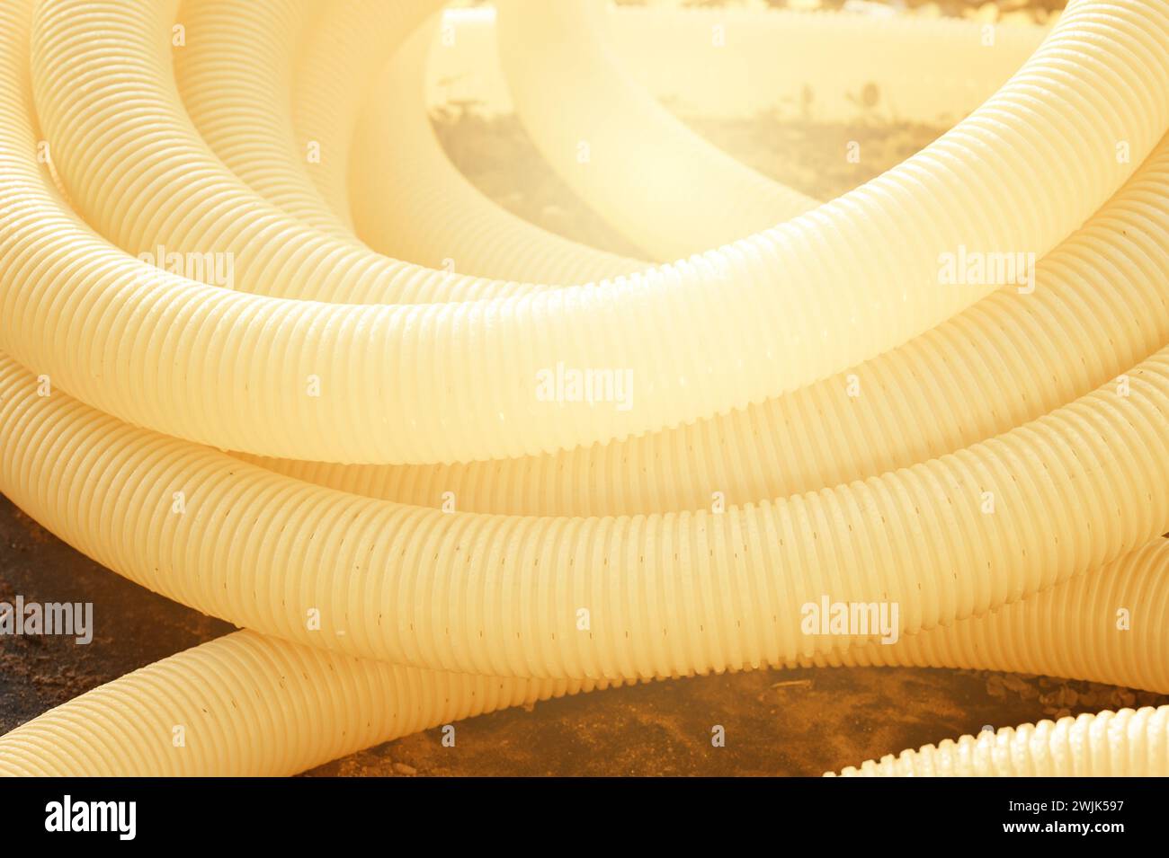 Perforated yellow drainage pipe with slots in a roll twisted in a ...