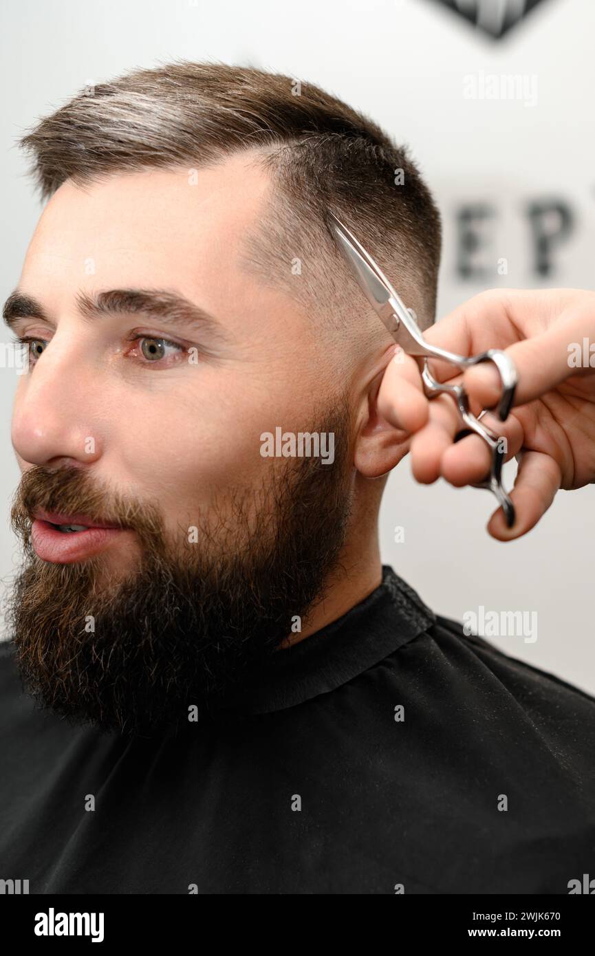 Haircut and alignment of the contour of the head with scissors. Short ...