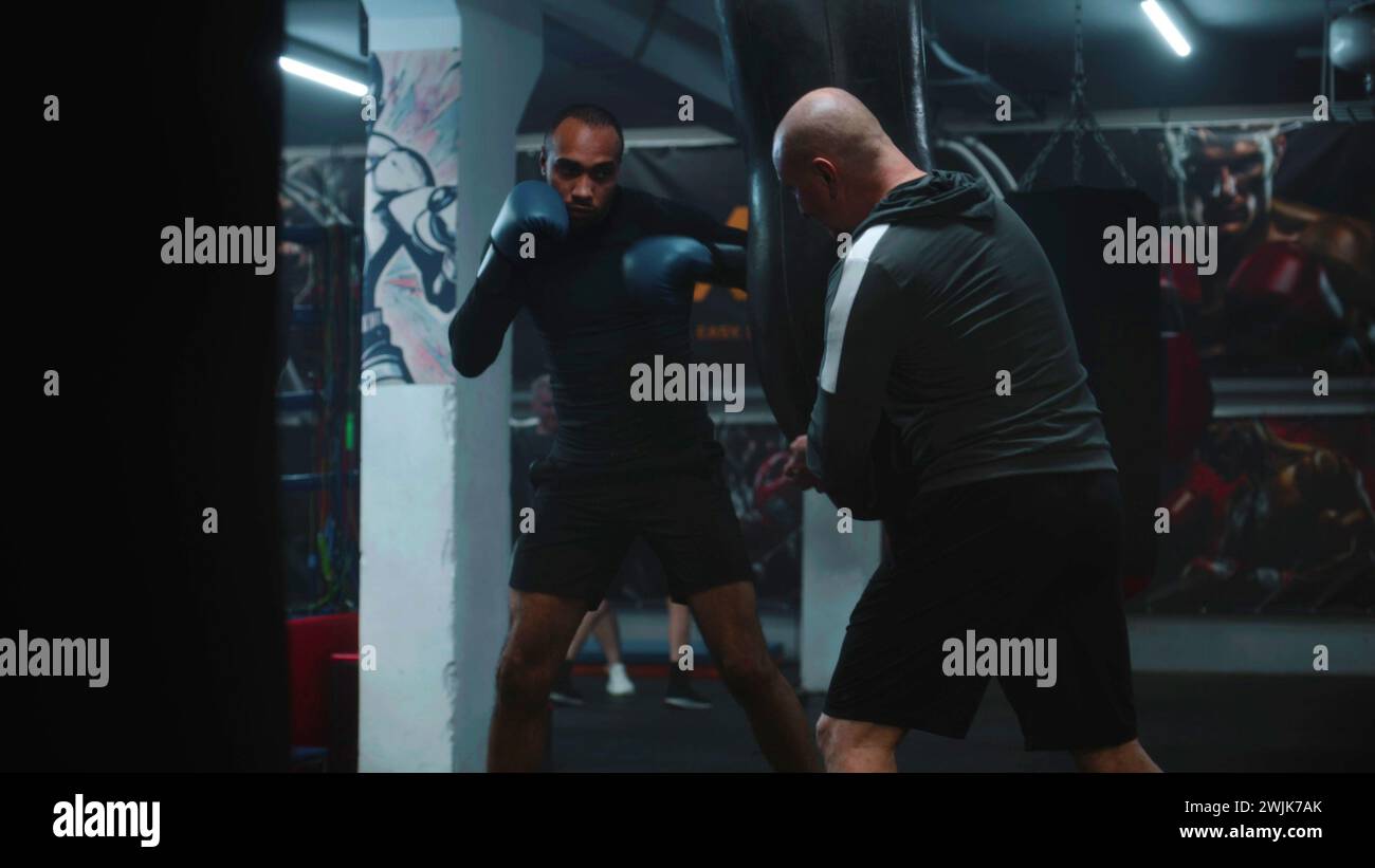 Confident African American fighter hits punching bag while training in ...