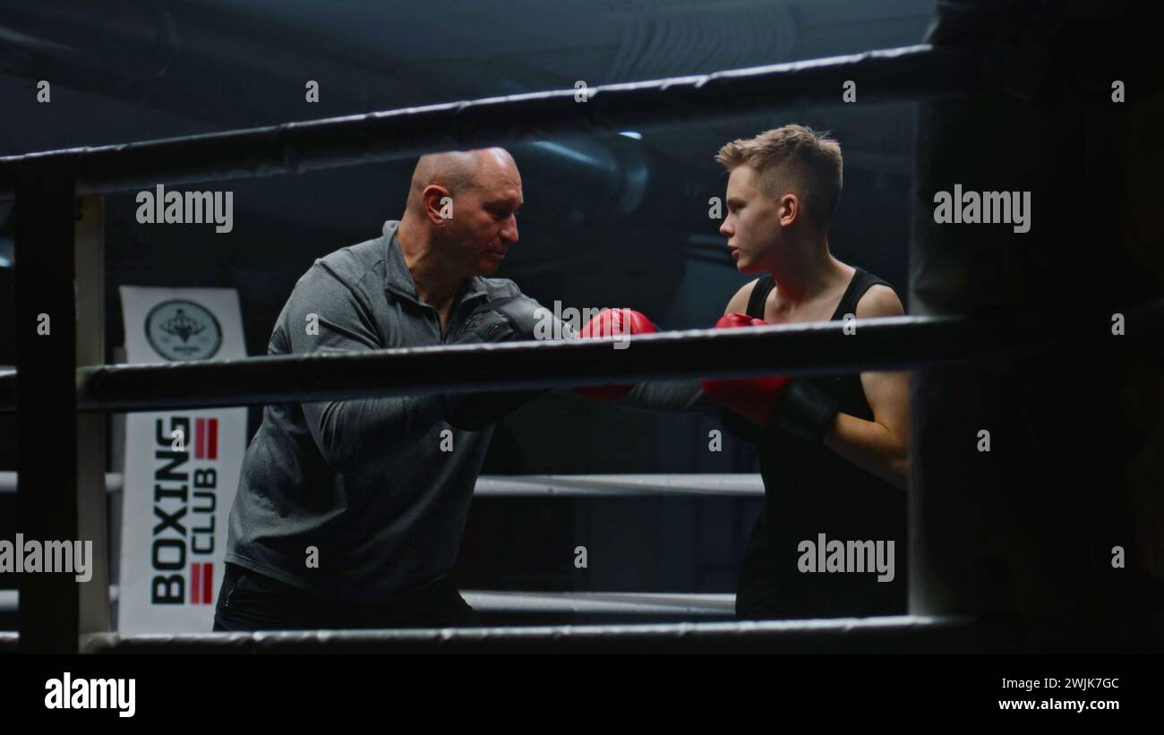 Professional coach teaches young boxer how to dodge punches on boxing ...