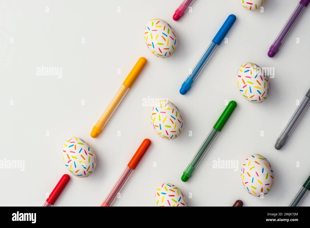 Painted Easter eggs with coloring pens aligned on white background with ...