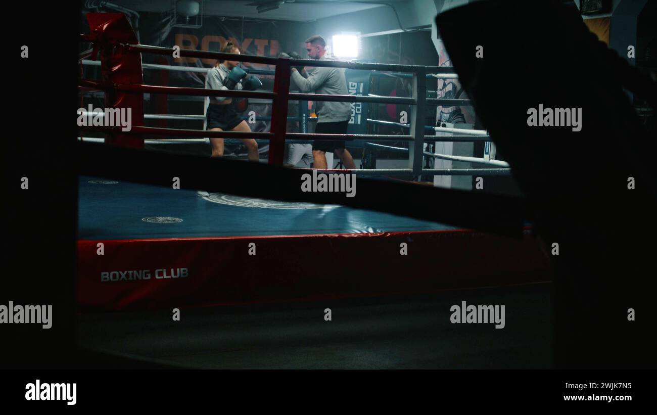 Female boxer in boxing gloves practices fighting technique with male ...
