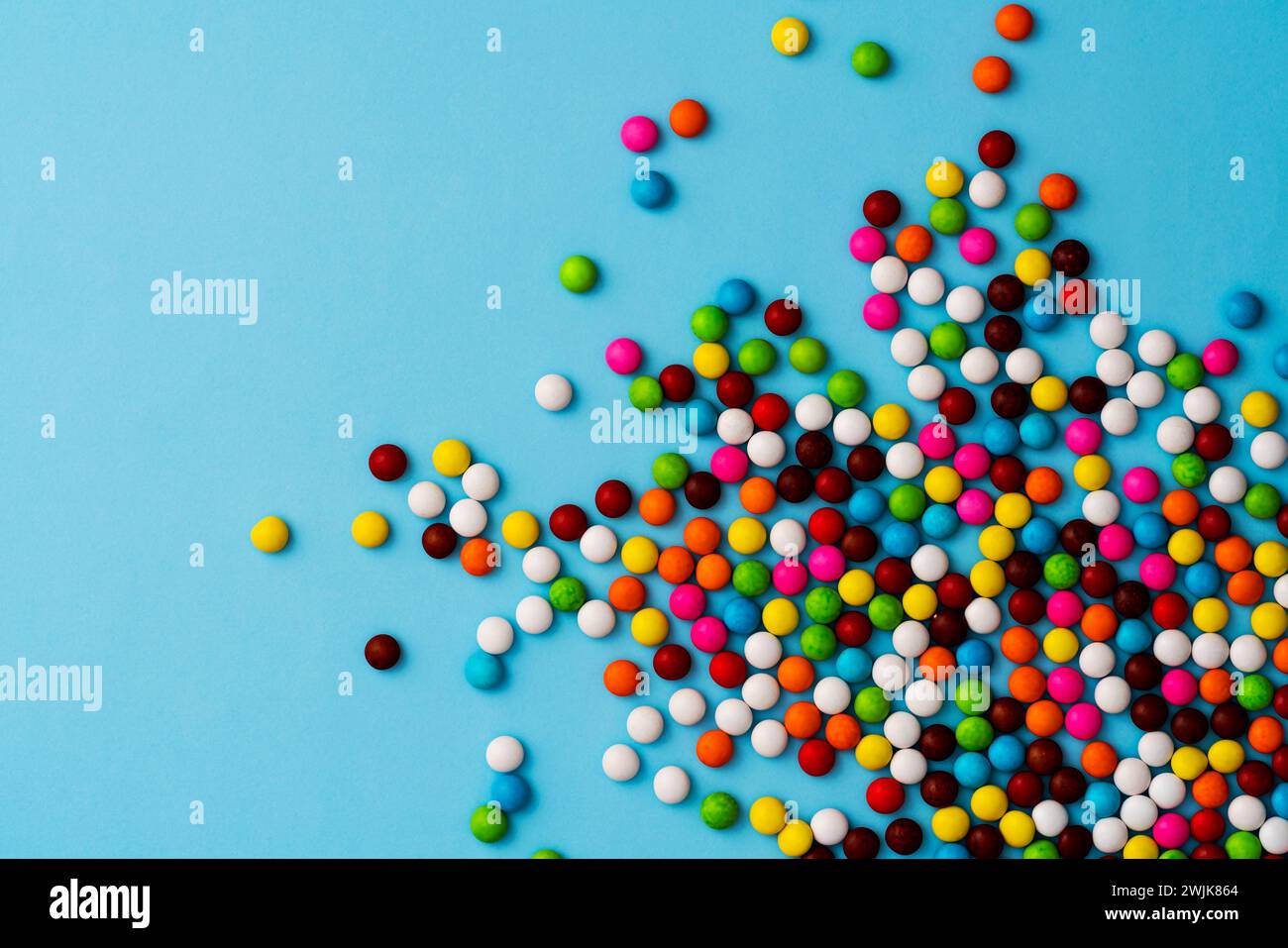 Colourful chocolate bean candies on blue background. Directly above ...