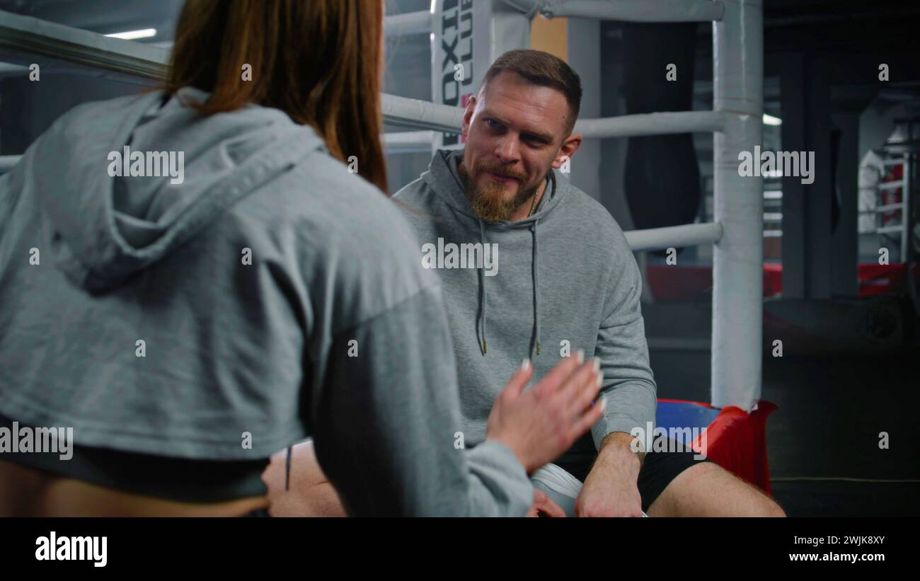 Female boxer sits on ring and talks with male trainer about fight ...