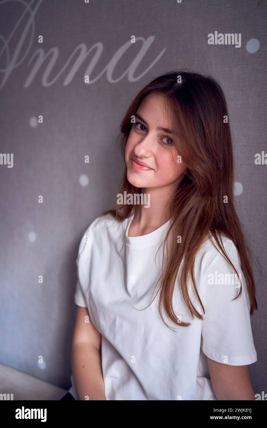 beautiful teenage girl sits on a bed near the wall with her name ...