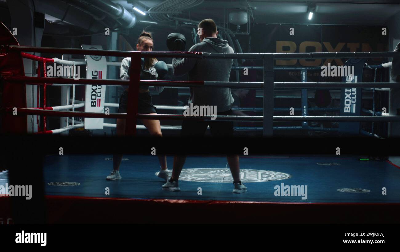 Female fighter in boxing gloves practices fighting technique with male ...