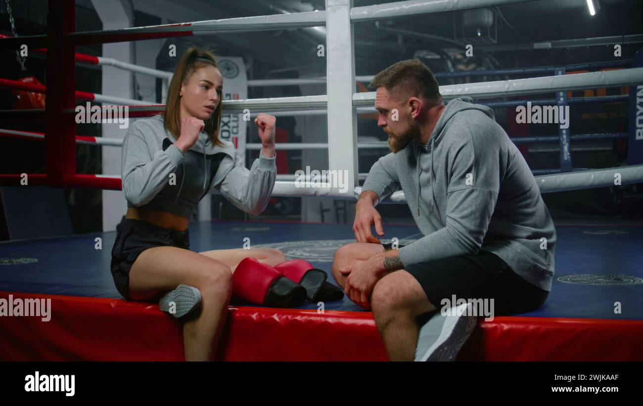 Female boxer sits with coach at boxing ring and discusses fight ...