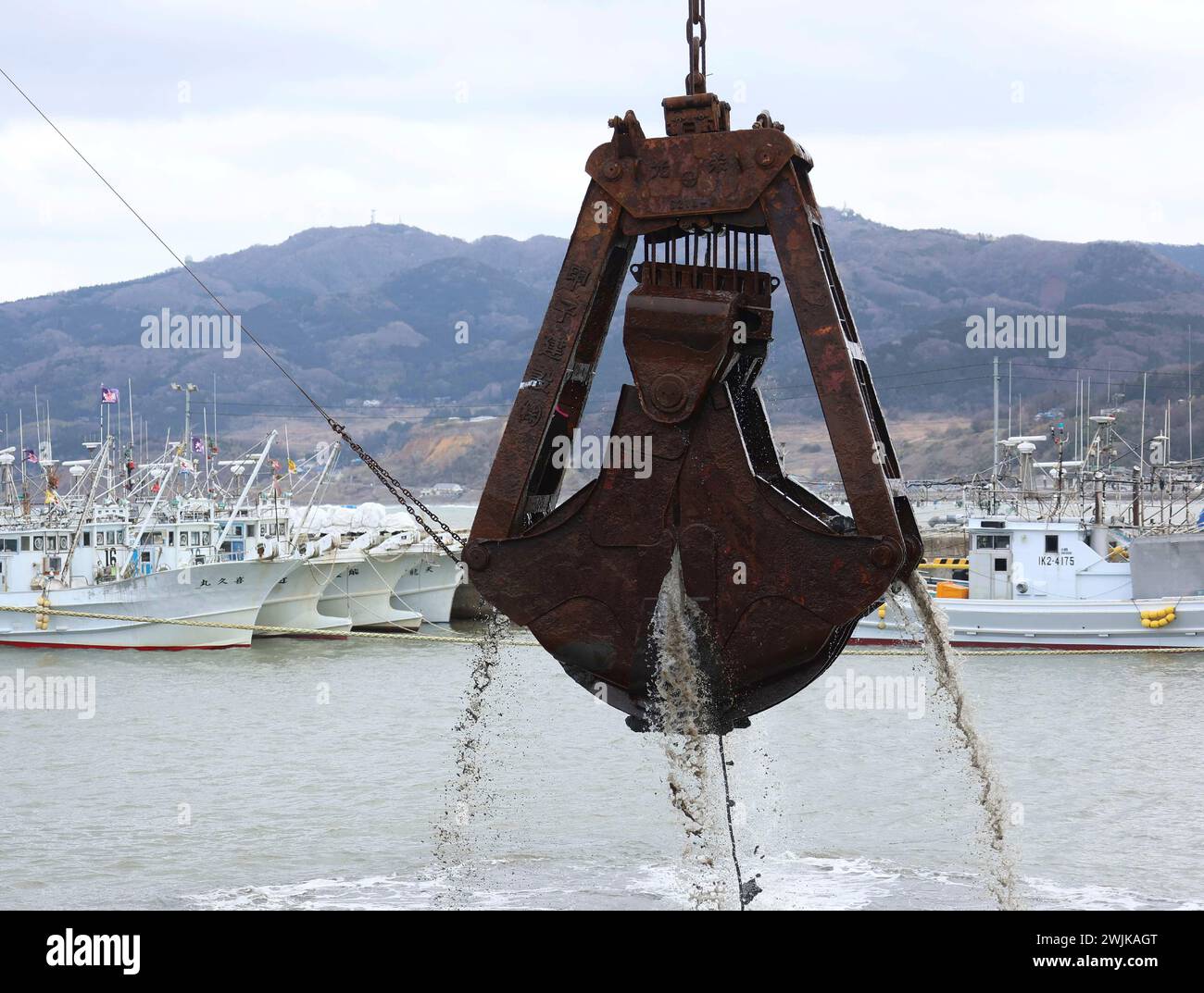 A worker removes accumulated sea sediment to pave the ship dock at the ...