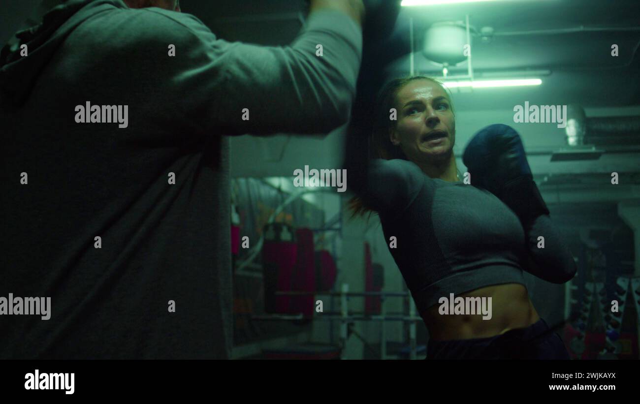 Young female boxer in boxing gloves exercises, talks with trainer in ...