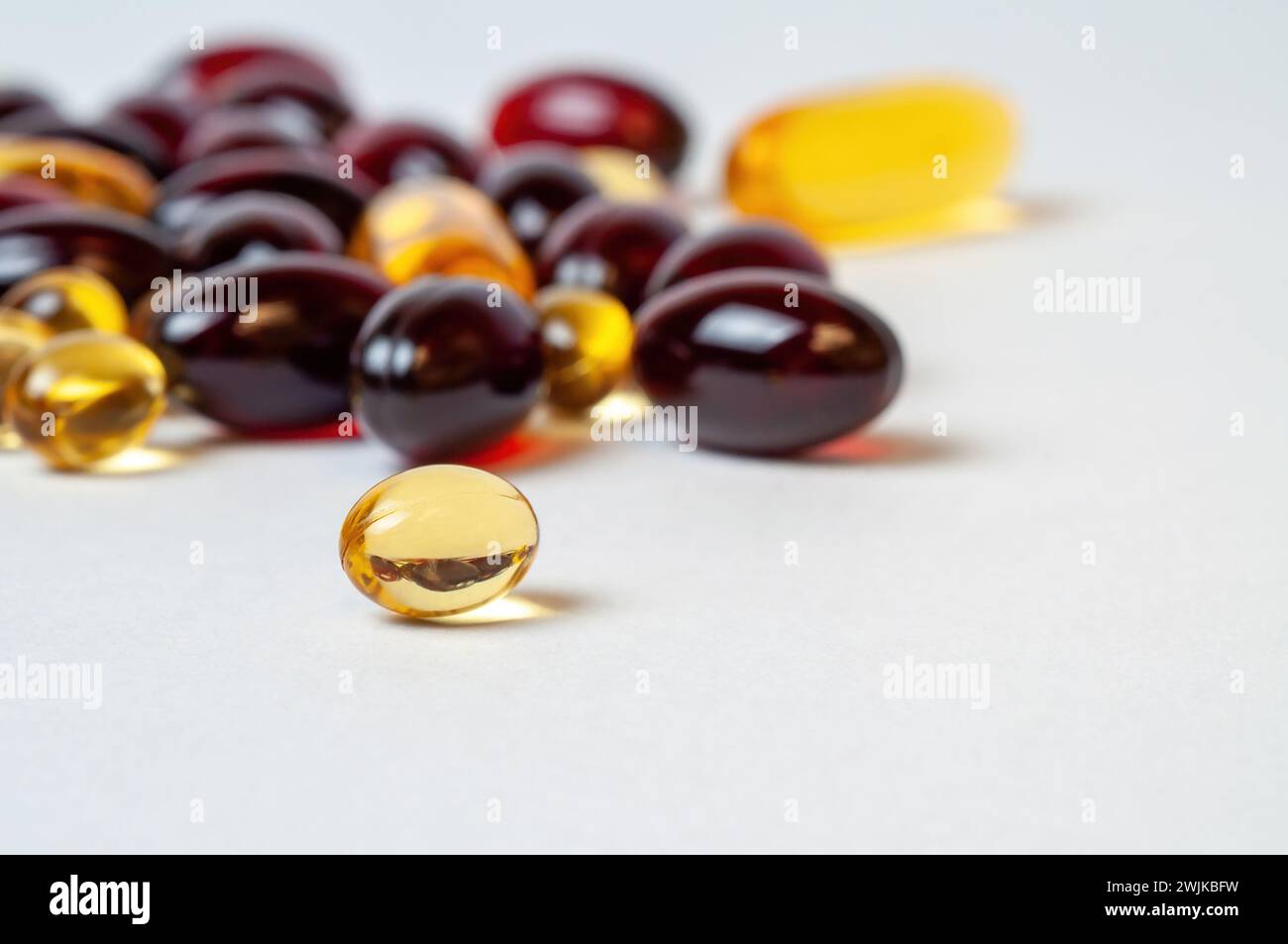 Various dietary supplement on a white surface, glossy pills scattered ...
