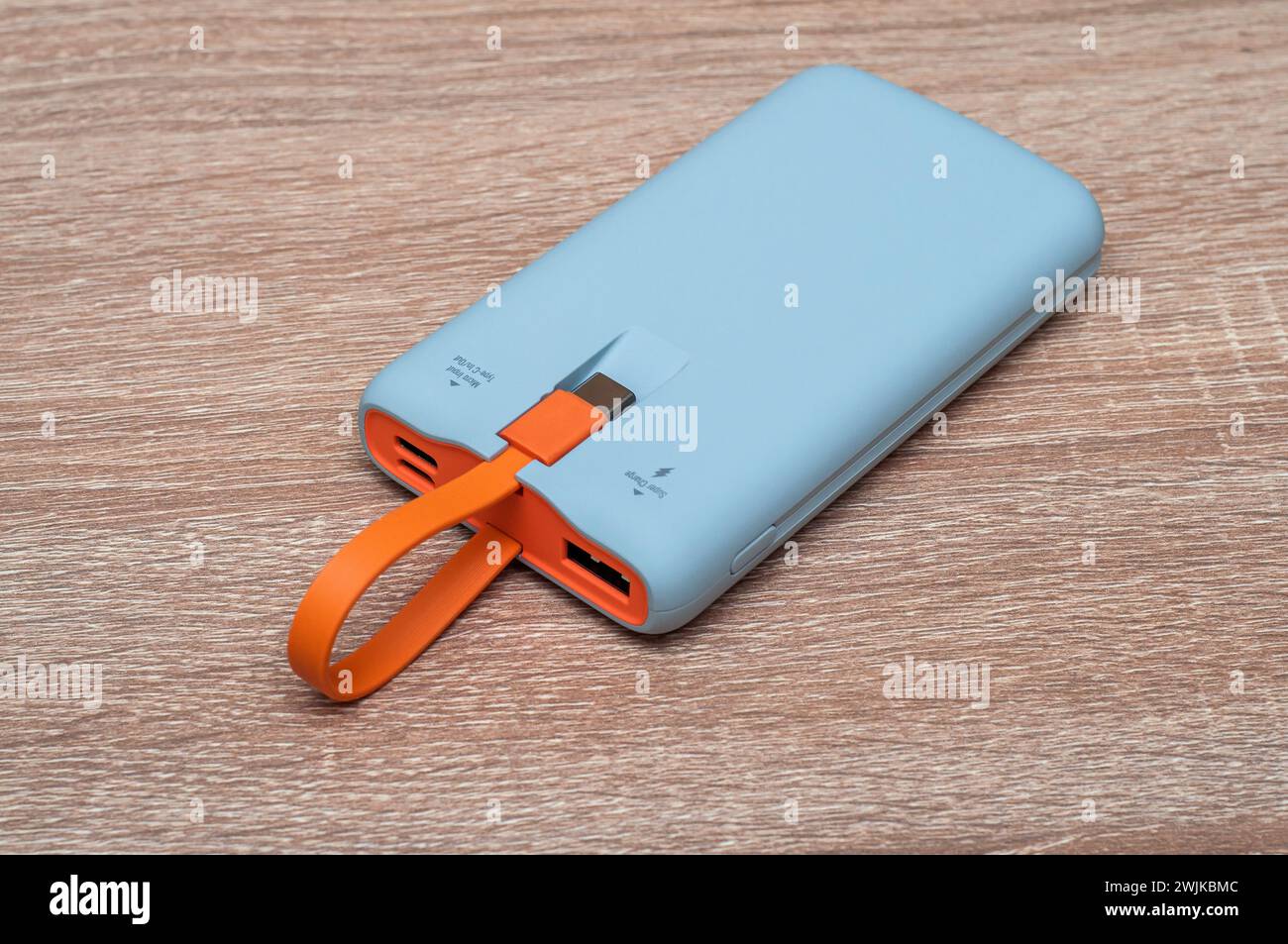 The power bank is gray with an orange USB handle, with connectors ...