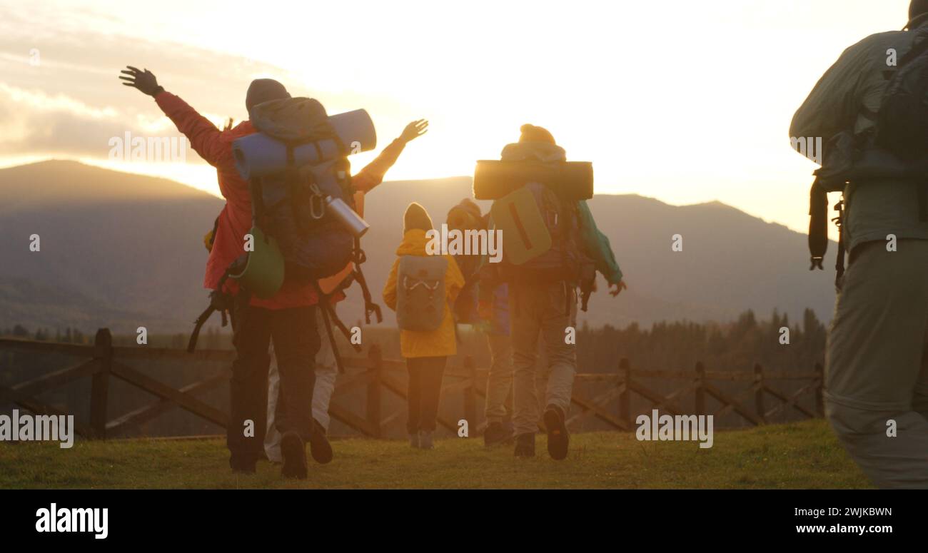 Diverse hikers with backpacks and trekking poles go hiking in mountains ...