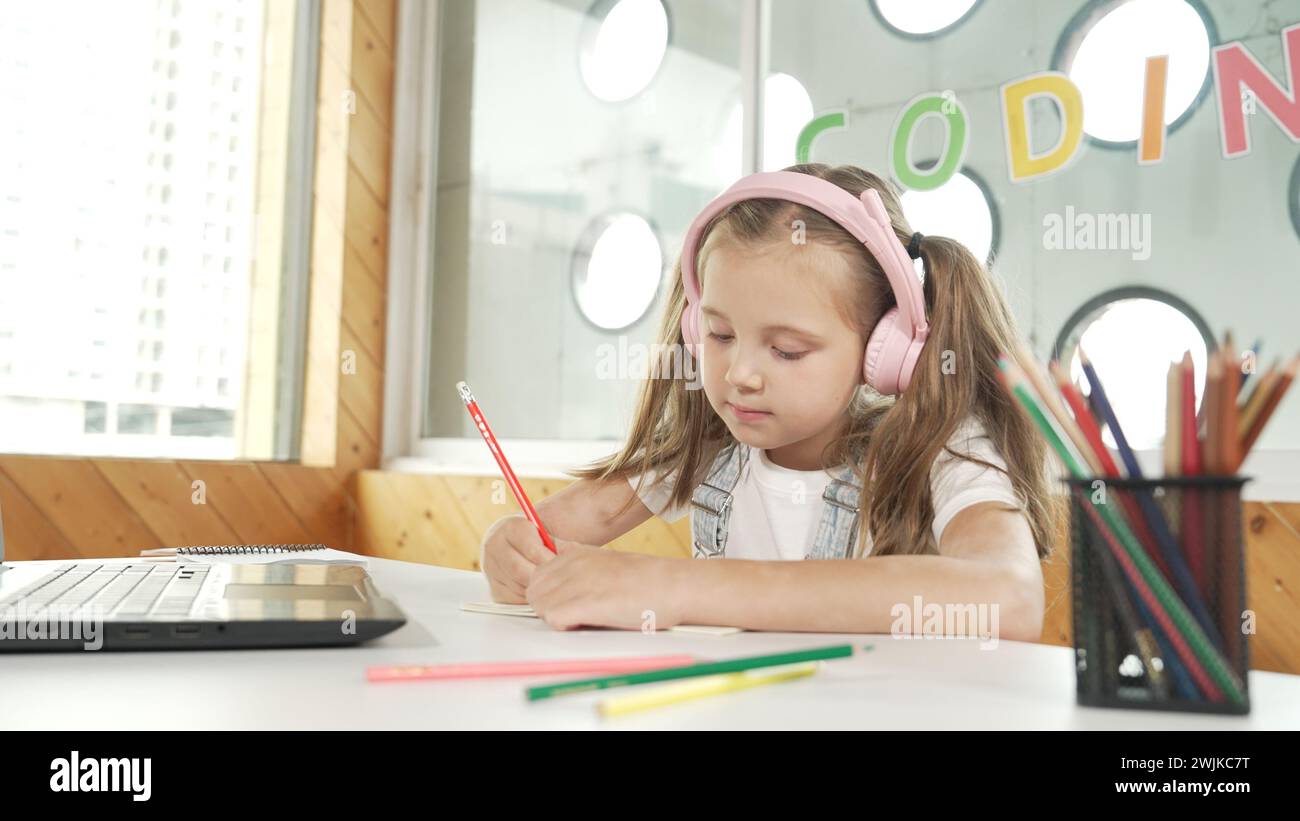 Cute smart girl doing classwork or online learning while listen to ...