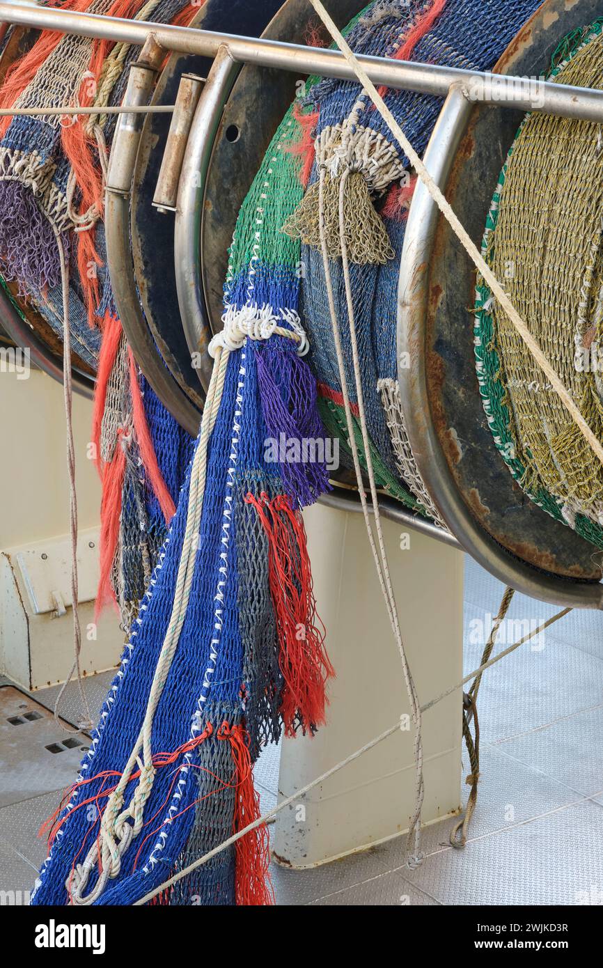 Rolled up industrial multi-coloured fishing nets on a winch aboard a ...