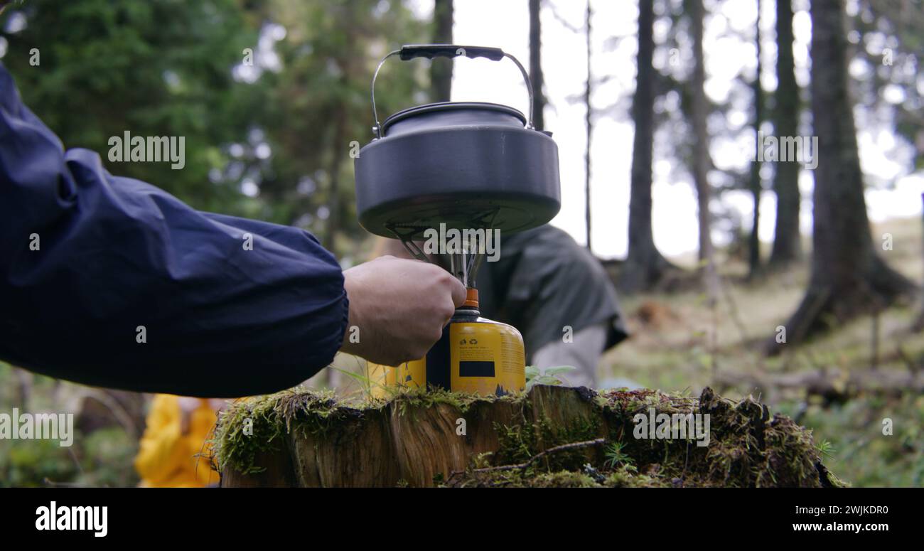 Tourist kettle stands on portable camping gas stove. Male traveler ...