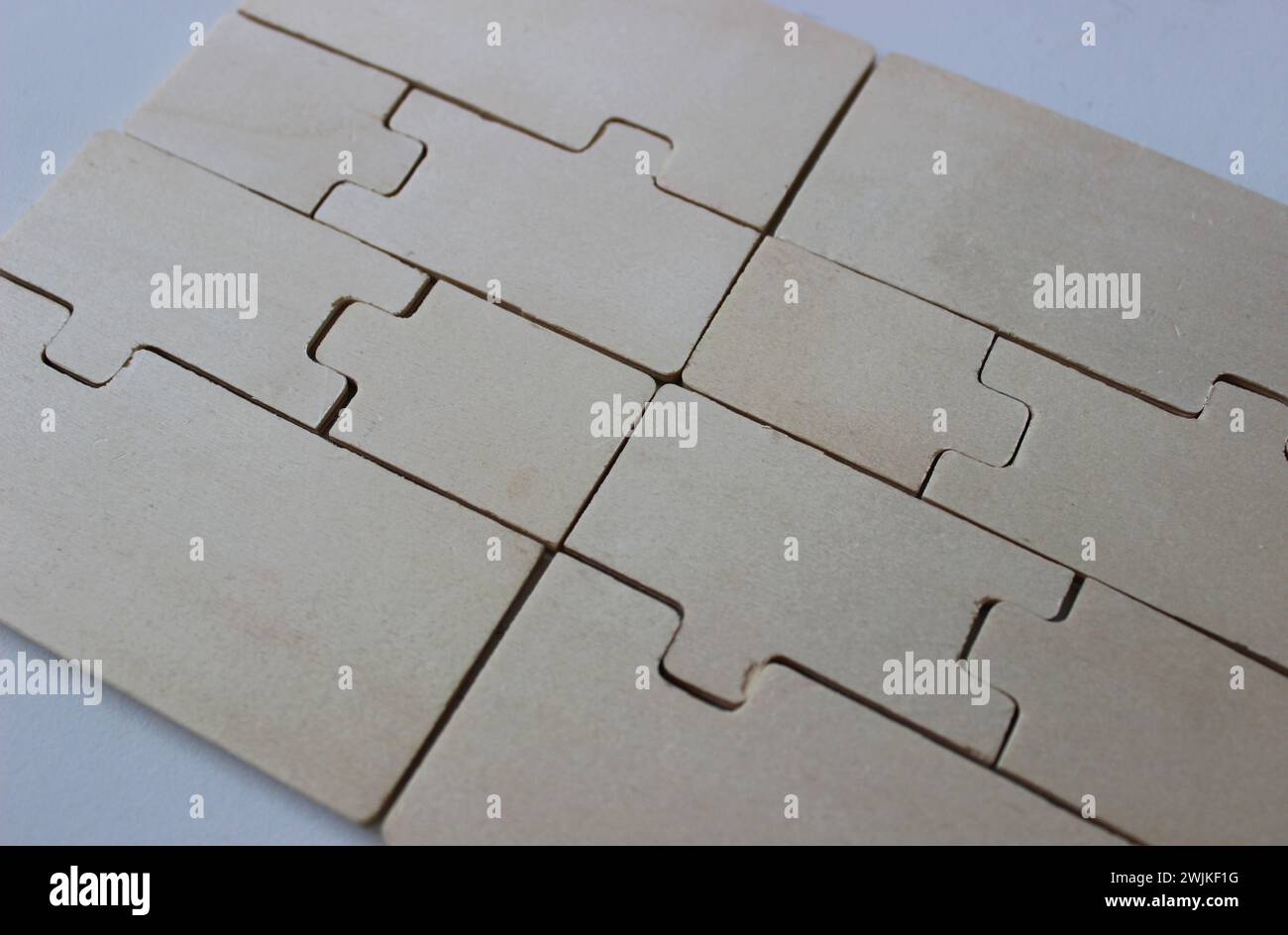 Rectangular panel of tightly folded plywood puzzles on a white surface ...