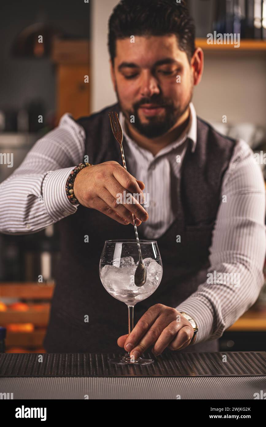 Professional bartender at work in bar mixing ice with vodka in glass for drink Stock Photo - Alamy