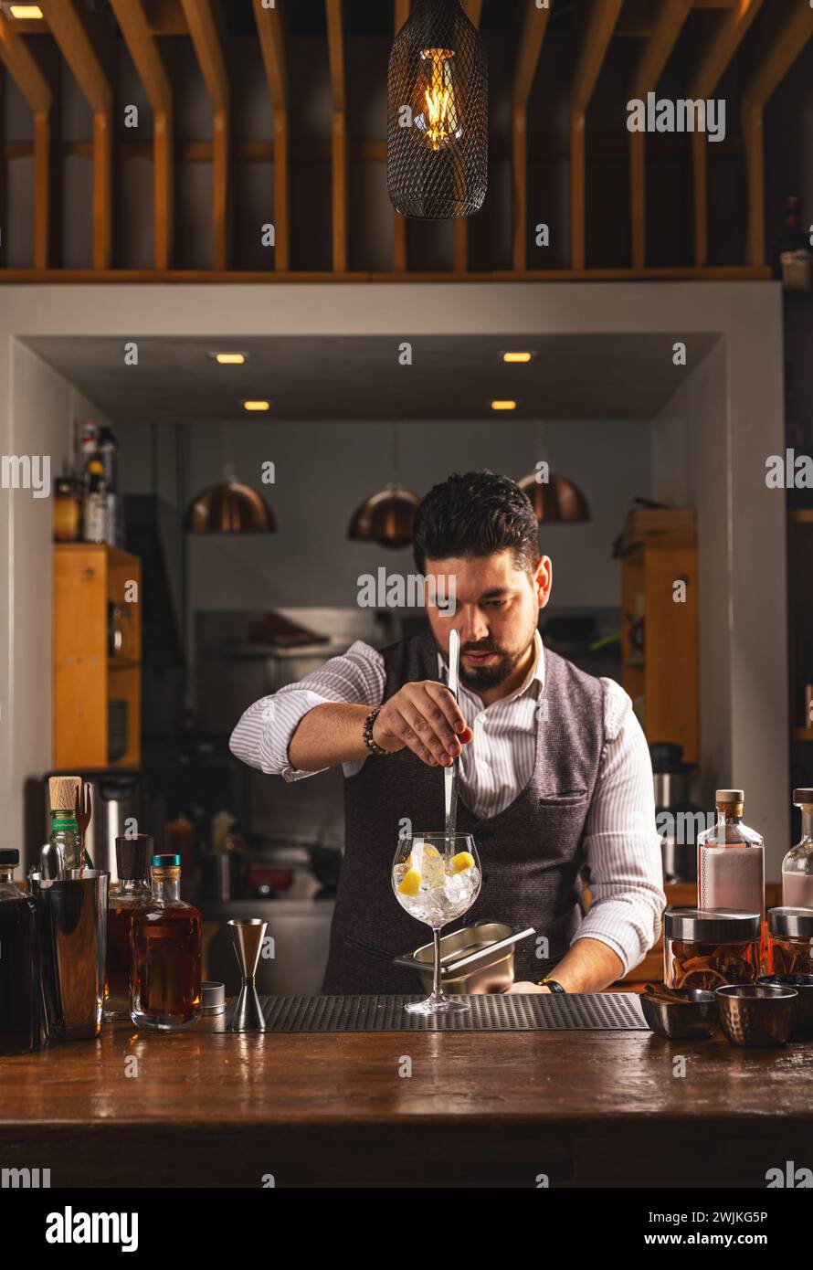 Professional bartender at work in bar mixing ice with vodka in glass for drink Stock Photo - Alamy