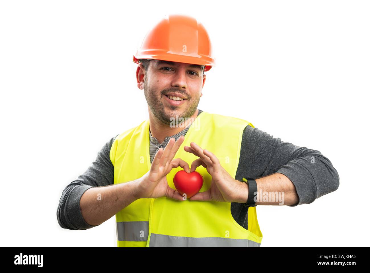 Happy builder man making cheerful friendly expression holding red heart ...