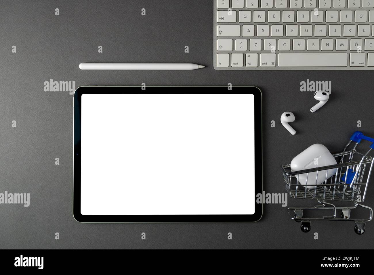 Tablet with blank screen, keyboard and supermarket cart on dark gray ...