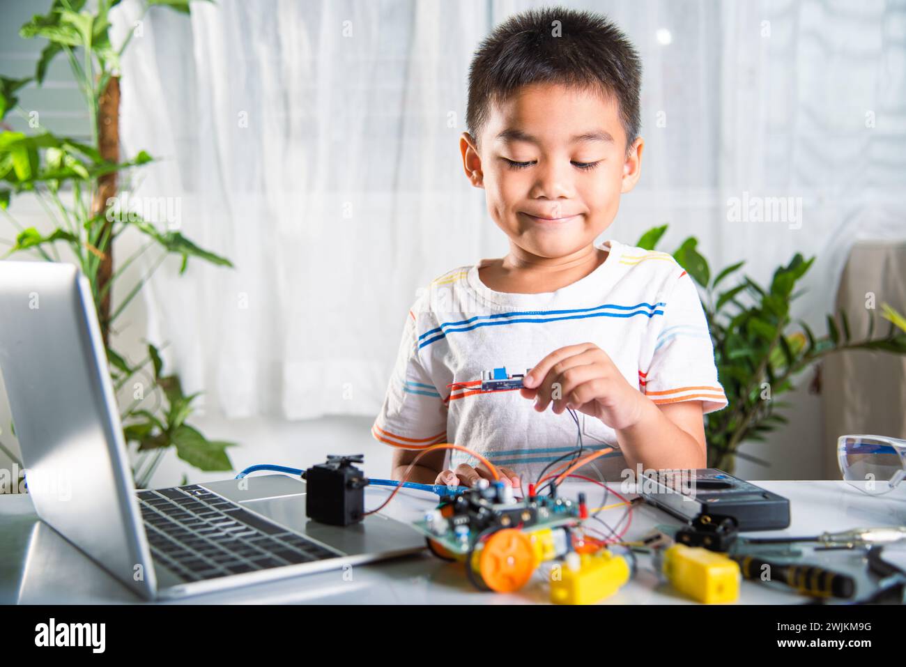 Asian kid boy assembling board into Arduino robot car homework Stock ...