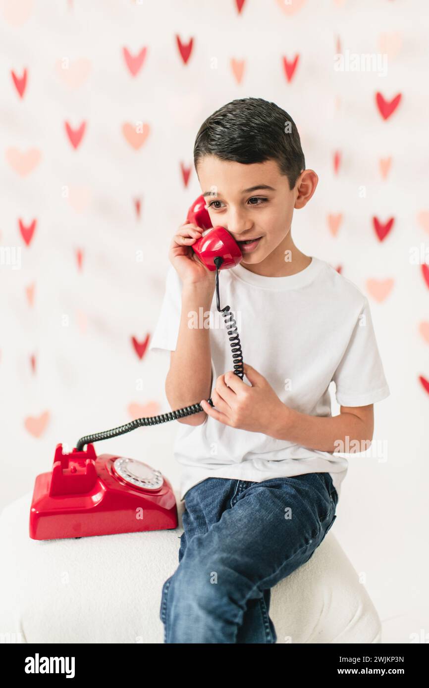 Boy talking on a rotary phone with cord against a heart backdrop Stock ...