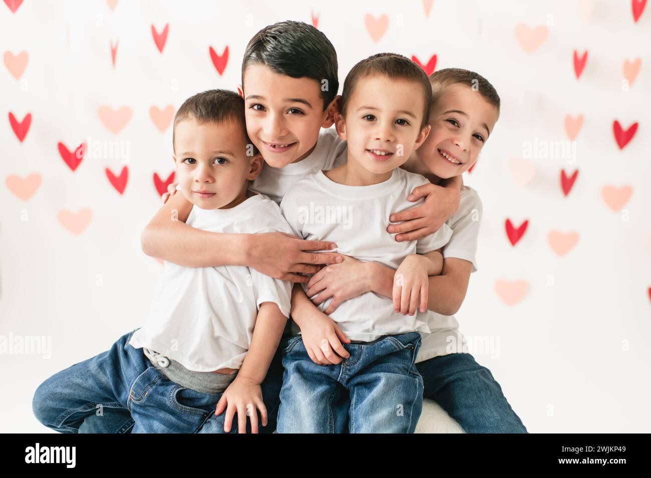 Happy children smiling and hugging against a heart backdrop Stock Photo ...