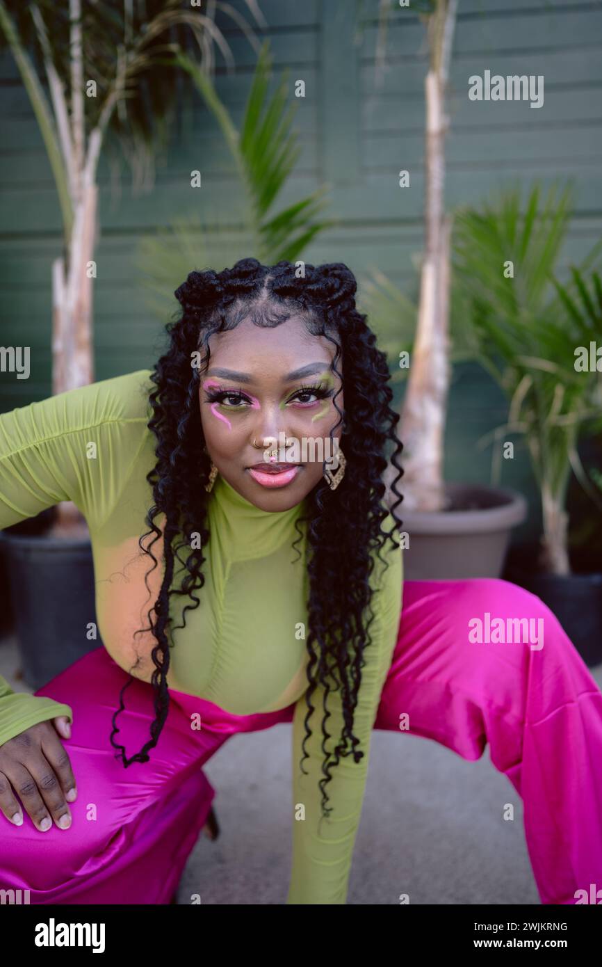 Model in neon outfit poses outside with colorful makeup Stock Photo - Alamy