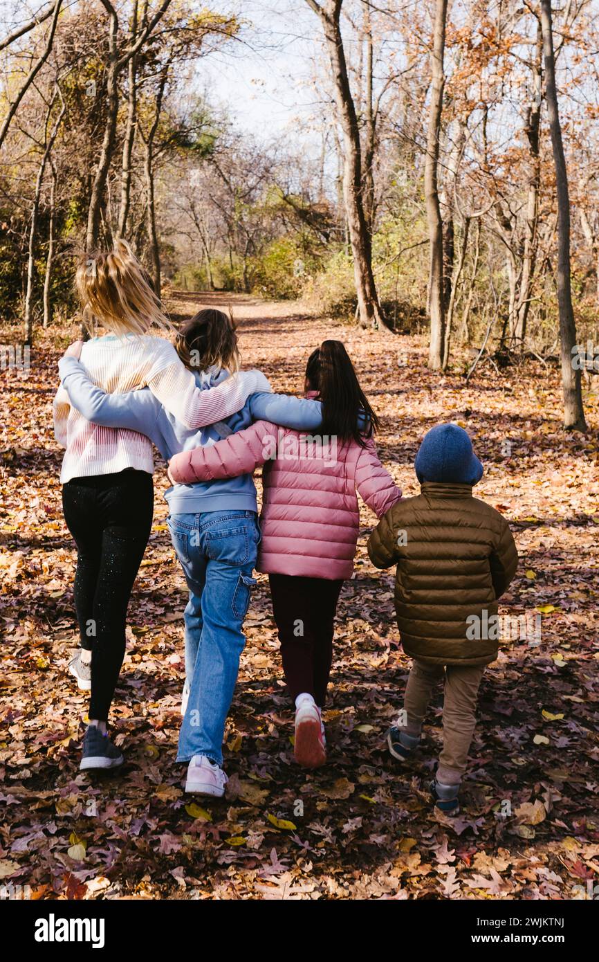 Kids hike through fall leaves on forest trail in sunshine Stock Photo ...