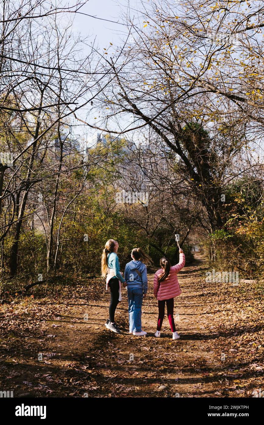 Girls on fall hike look up at trees and enjoy nature and wilderness ...