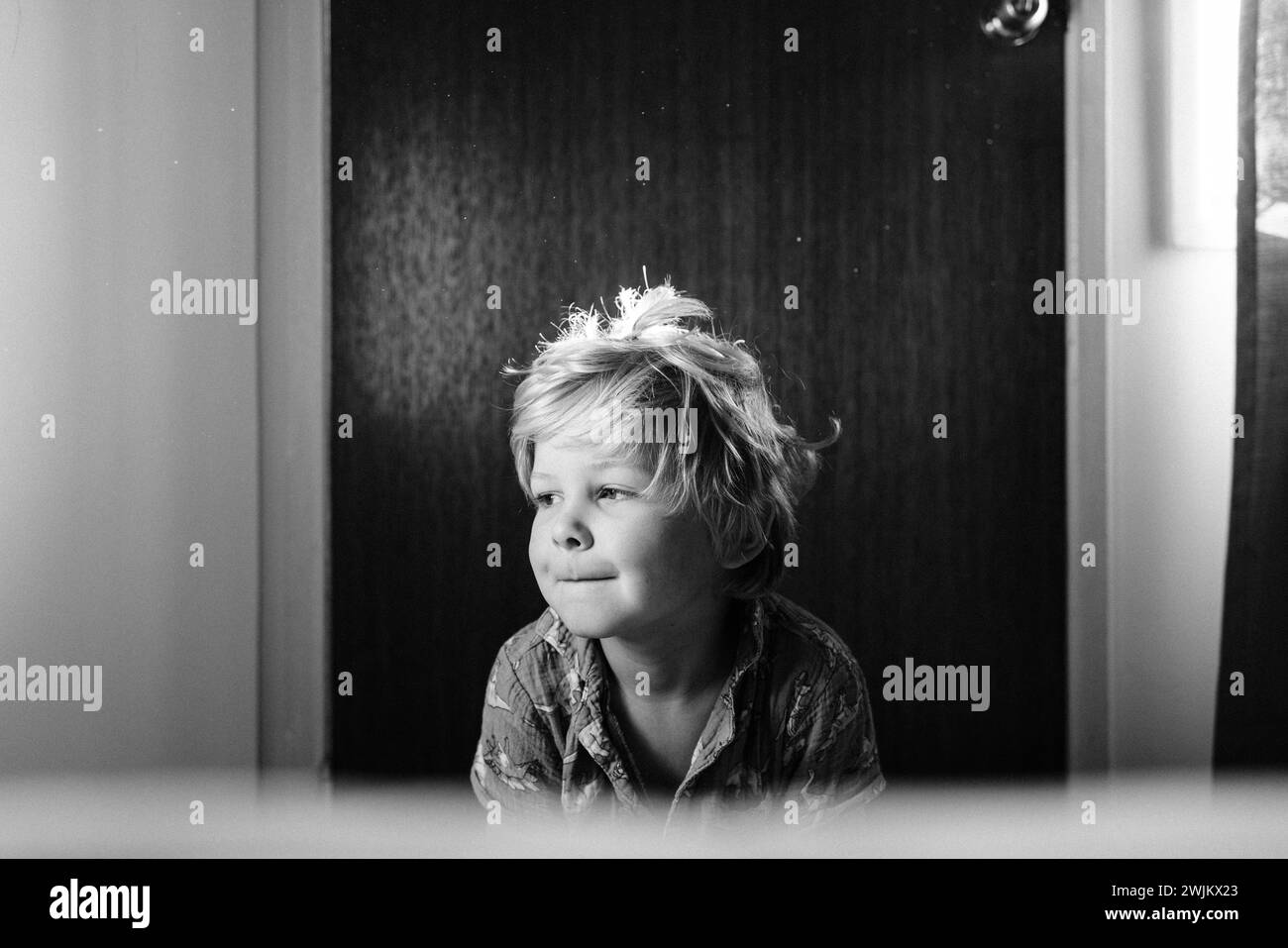 Blonde boy with smirk sitting indoors in a motel room Stock Photo - Alamy