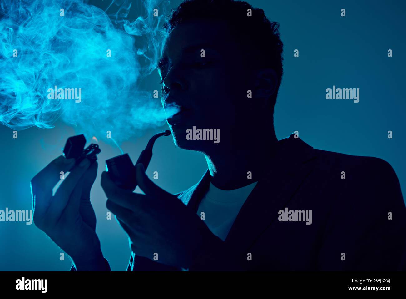 african american guy holding lighter and pipe while exhaling smoke on ...
