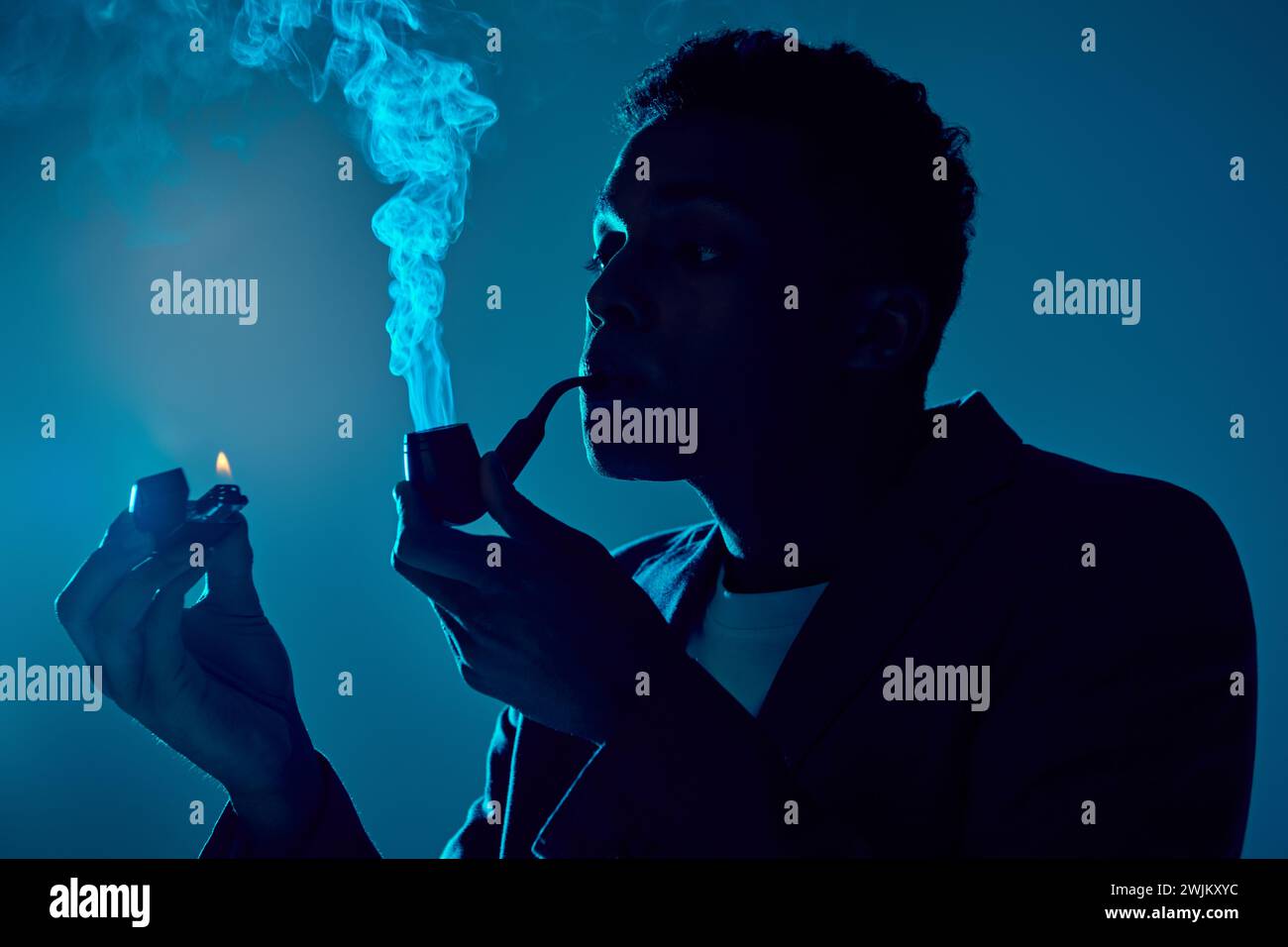 young african american guy holding lighter and pipe while exhaling ...