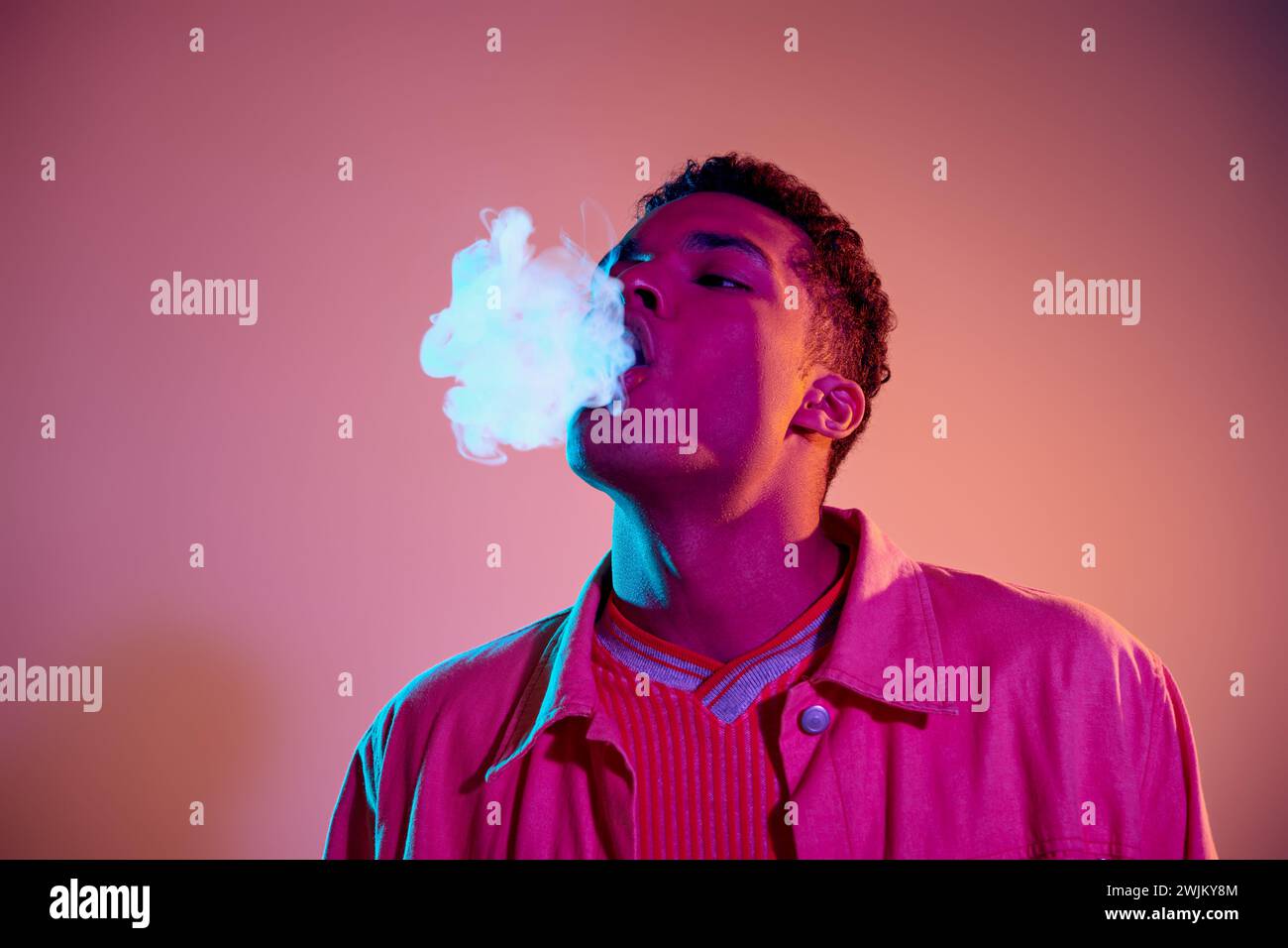 portrait of african american man exhaling smoke against vibrant ...