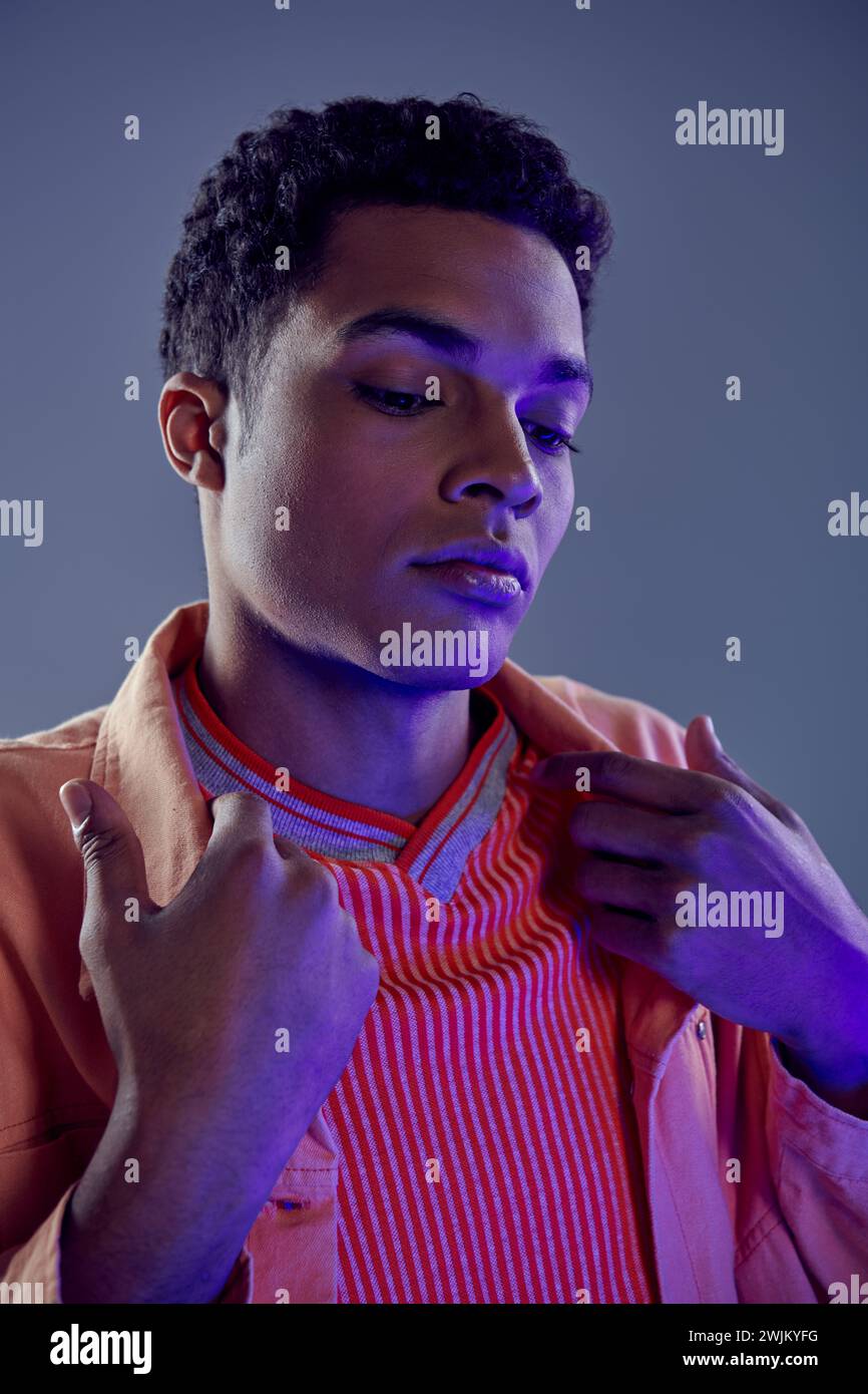 portrait of handsome african american man in peach shirt posing on grey ...