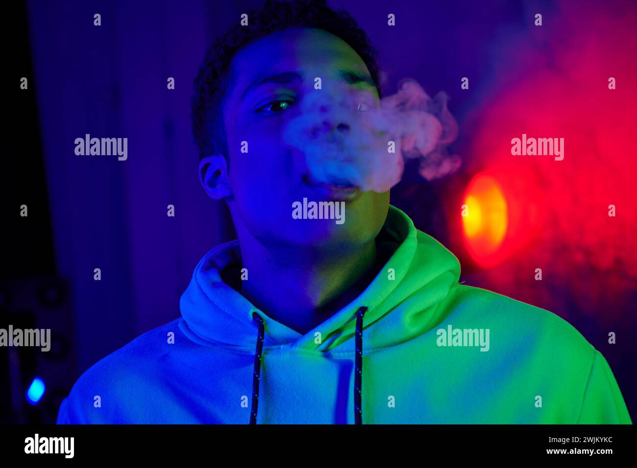 serious african american man exhaling smoke on dark blue background ...