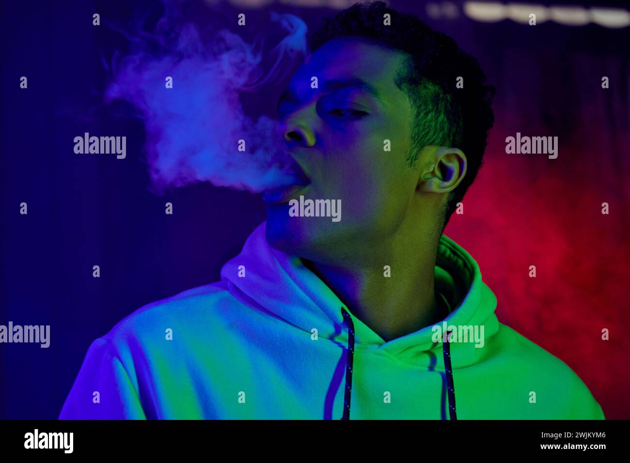 serious african american man exhaling smoke on dark background with ...