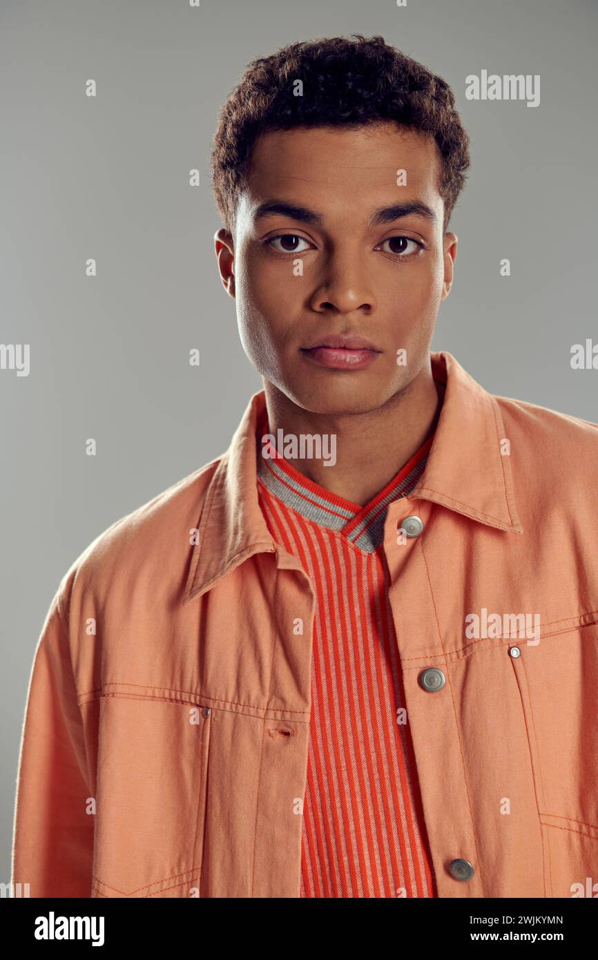 young african american man in peach color shirt looking at camera on ...
