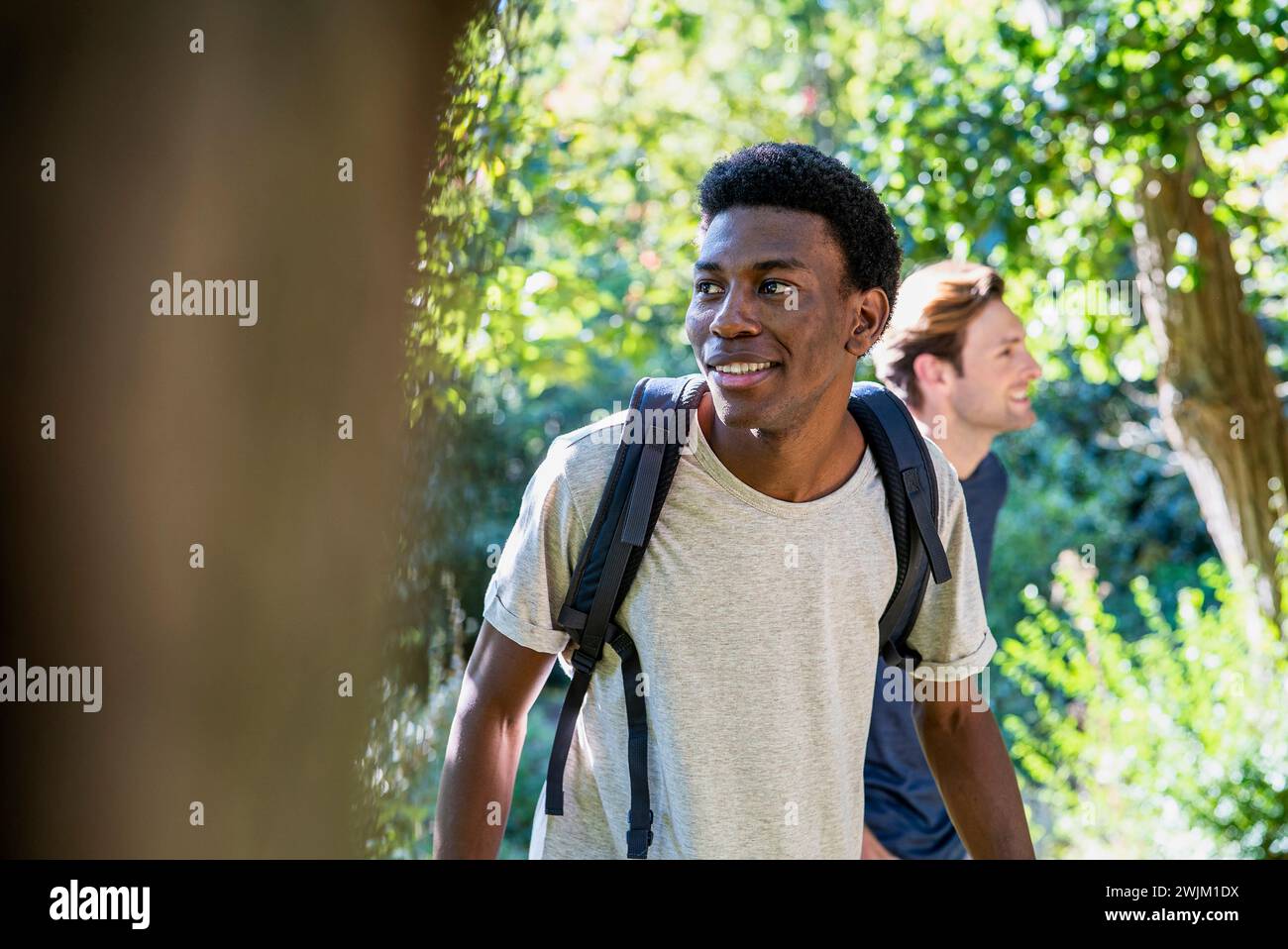 Young adult man wearing backpack during hiking with friends Stock Photo ...
