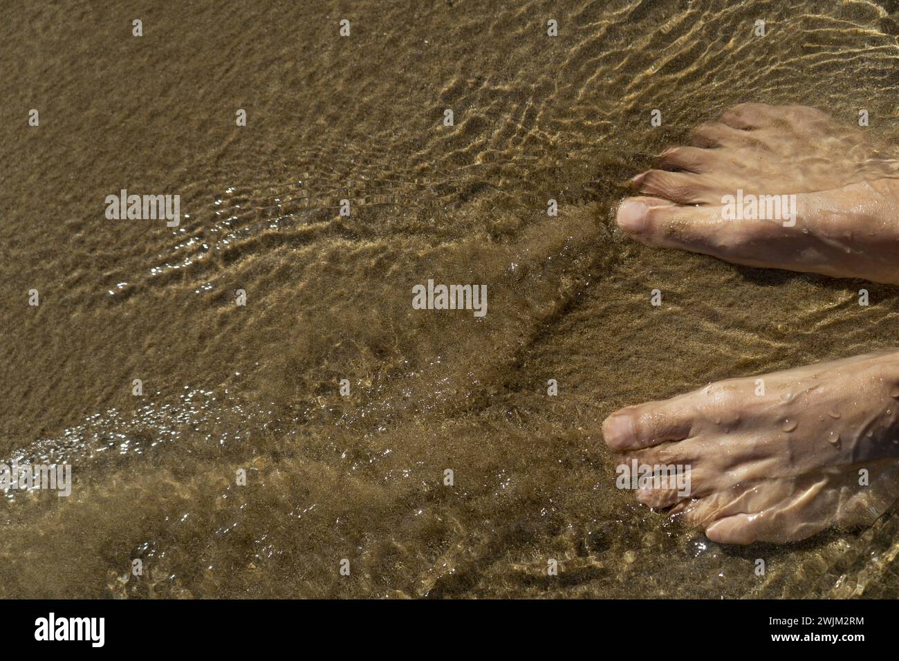 Unidentified person's feet inside running water at beach Stock Photo ...