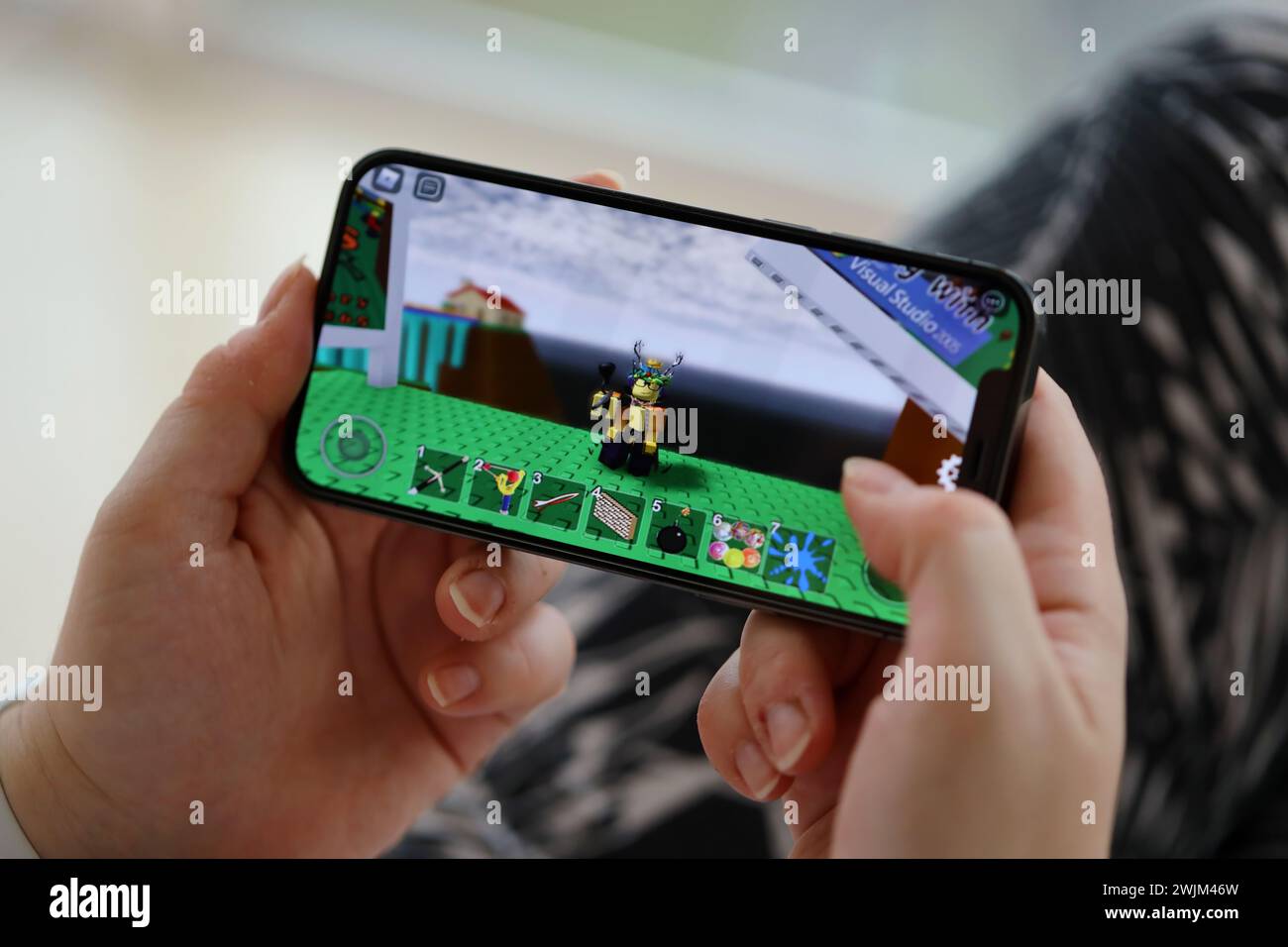 Roblox mobile iOS game on iPhone 15 smartphone screen in female hands ...