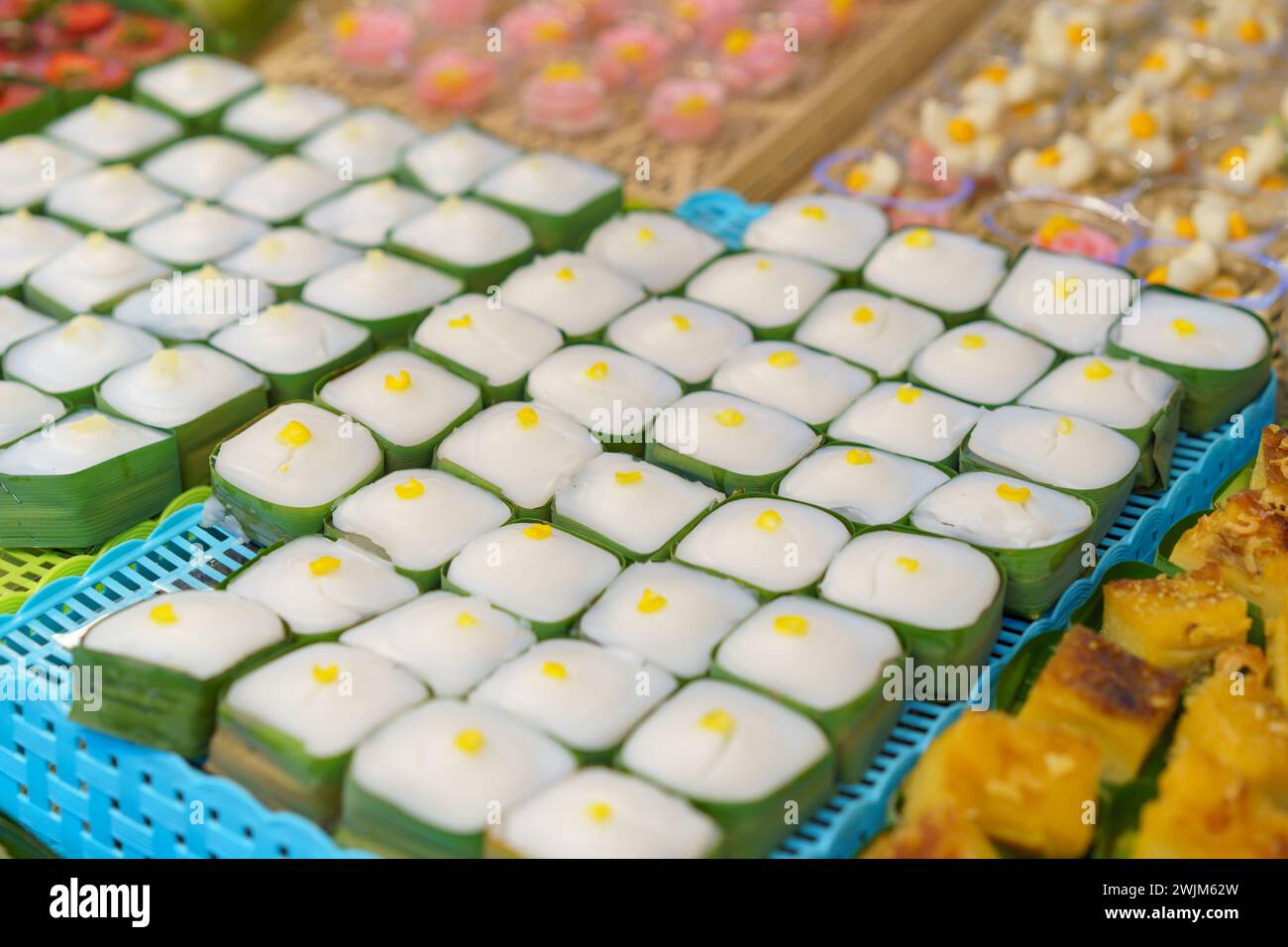 Thai pudding with coconut topping, known as 'Khanom Tako', presented in small banana leaf cups ...