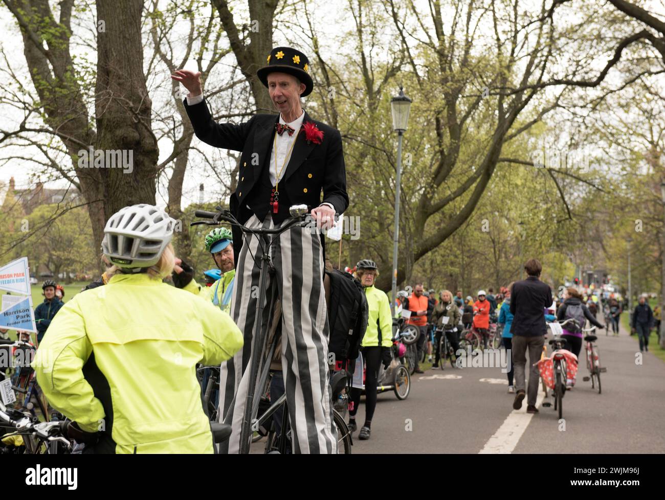 A man on a tall bike with stilts in front of hundreds of cyclists and ...