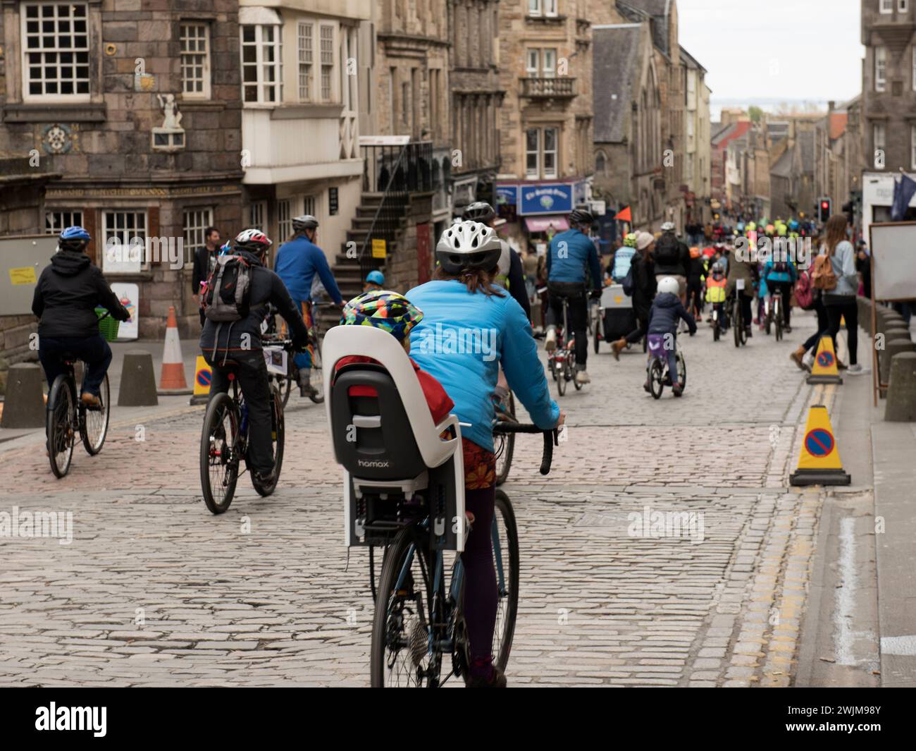 The back of a mother cycling with her child within hundreds of cyclists ...