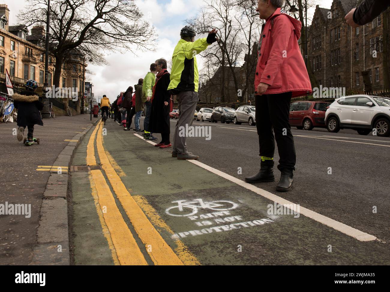 People line a bike lane to make a human bike lane to protest the lack ...